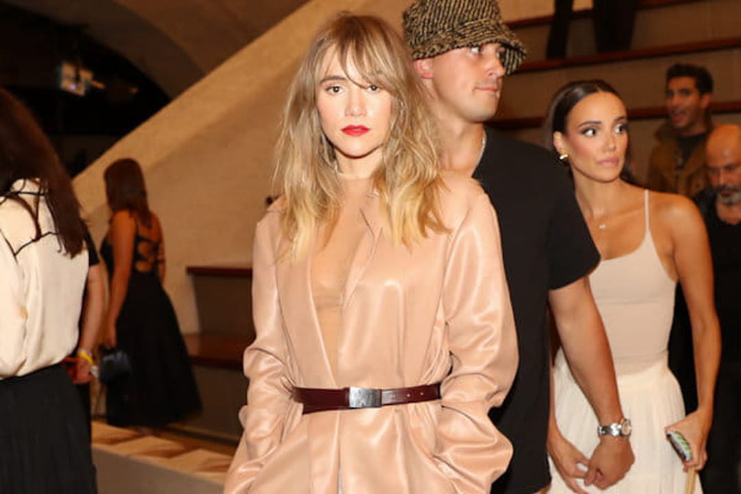 Suki Waterhouse en manteau en cuir rose poudré et longue robe grise au ...