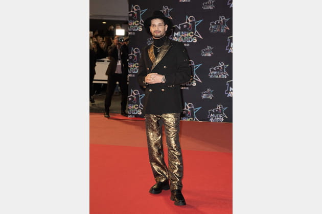 Soolking en costume noir et doré avec un chapeau