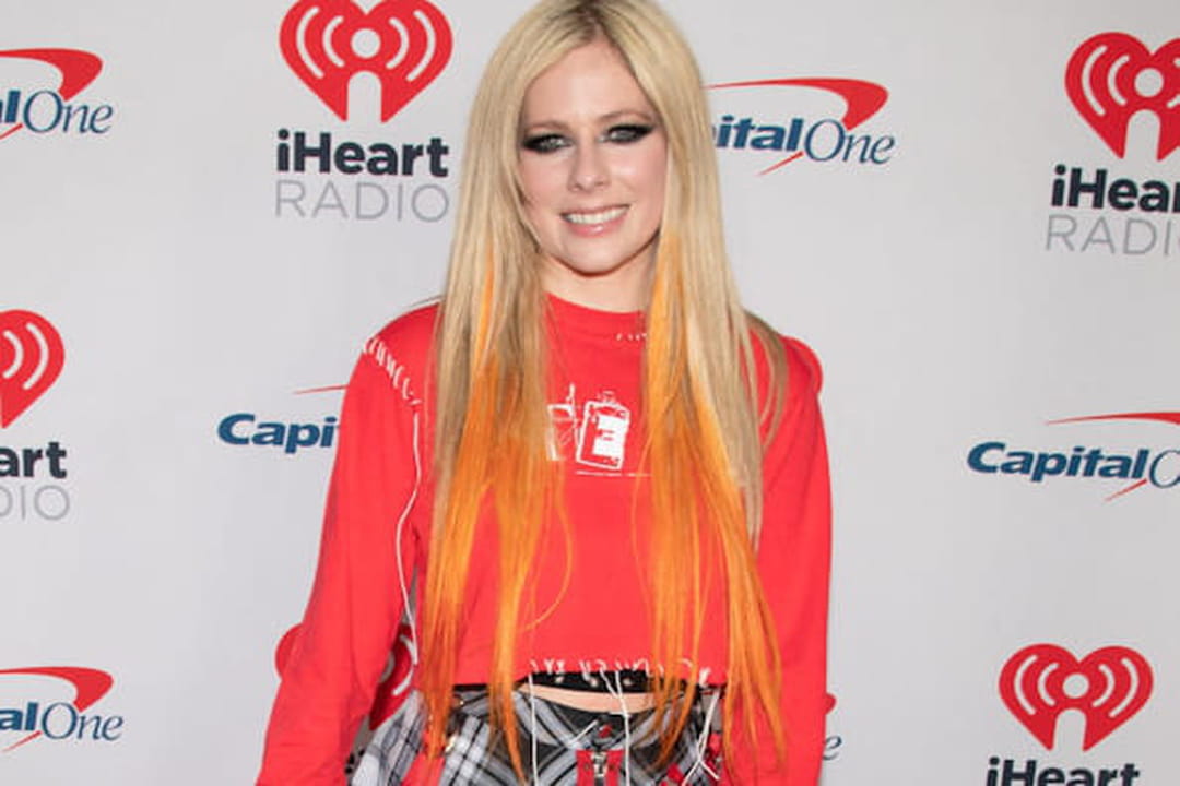 Avril Lavigne en jupe à carreaux et pull rouge