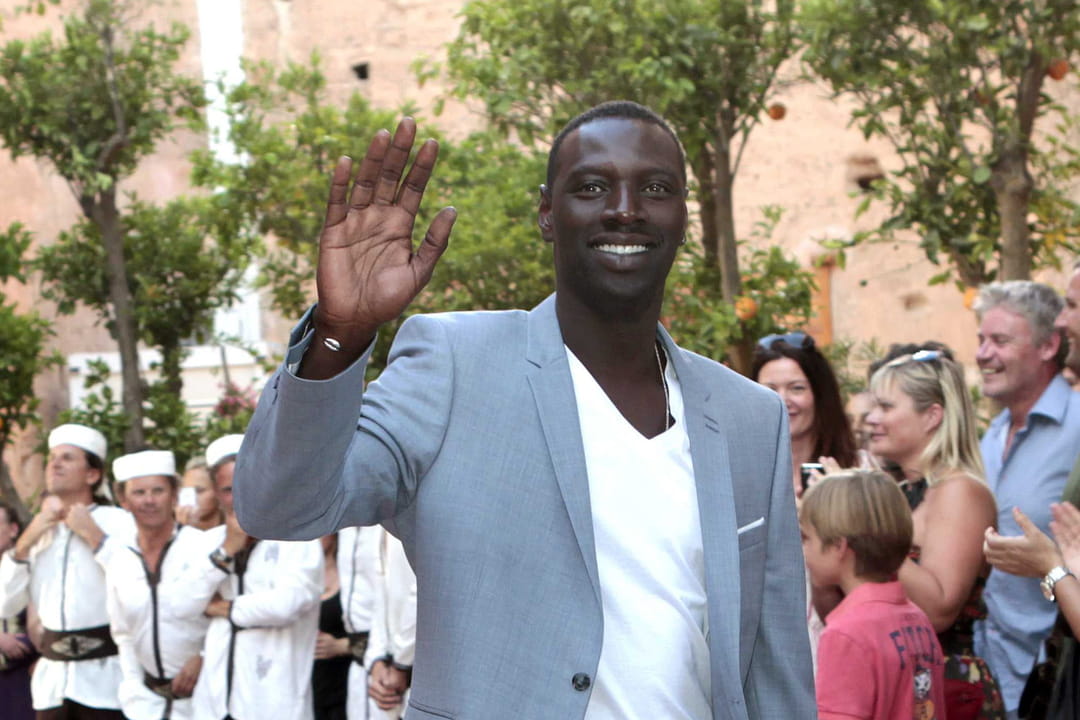Omar Sy en costume gris clair et T-shirt blanc