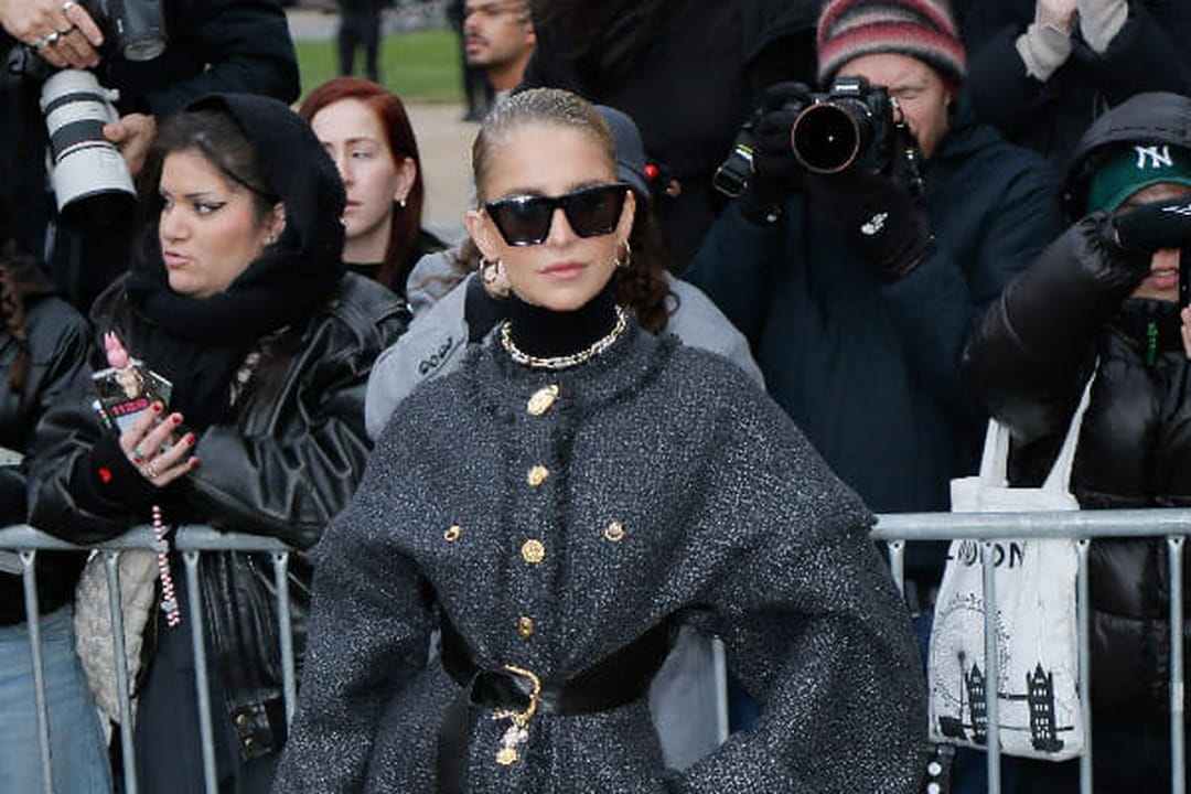 Caroline Daur en robe pull grise et sac à main doré au défilé ...