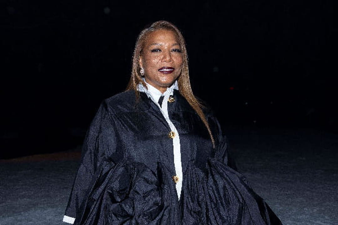 Queen Latifah en manteau à volants noir et sac à main horloge