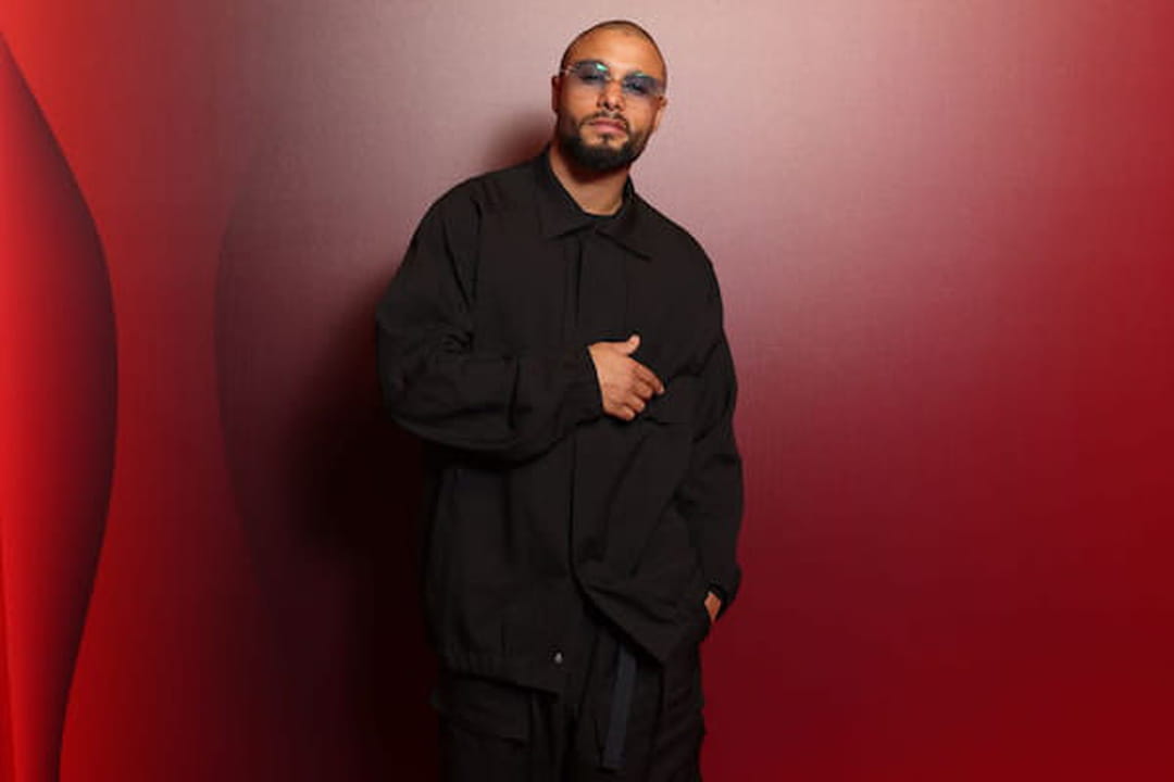 Sadeck en chemise noire ample et pantalon cargo à l'événement Louboutin